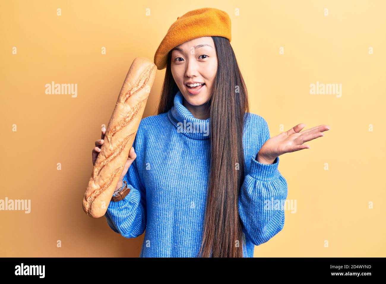 Young beautiful blonde woman wearing french beret holding bread ...