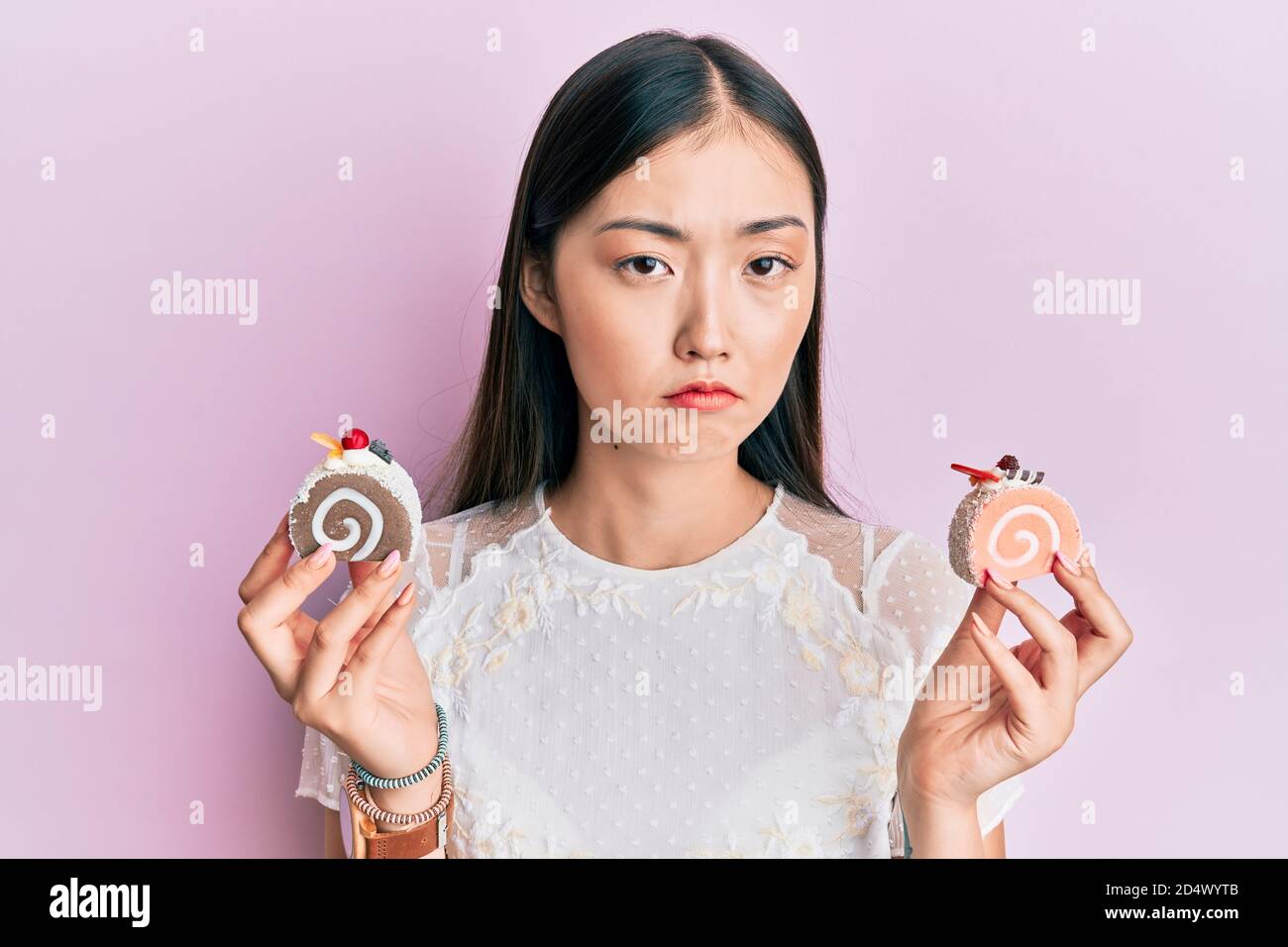 Young chinese woman holding cake sweets depressed and worry for ...