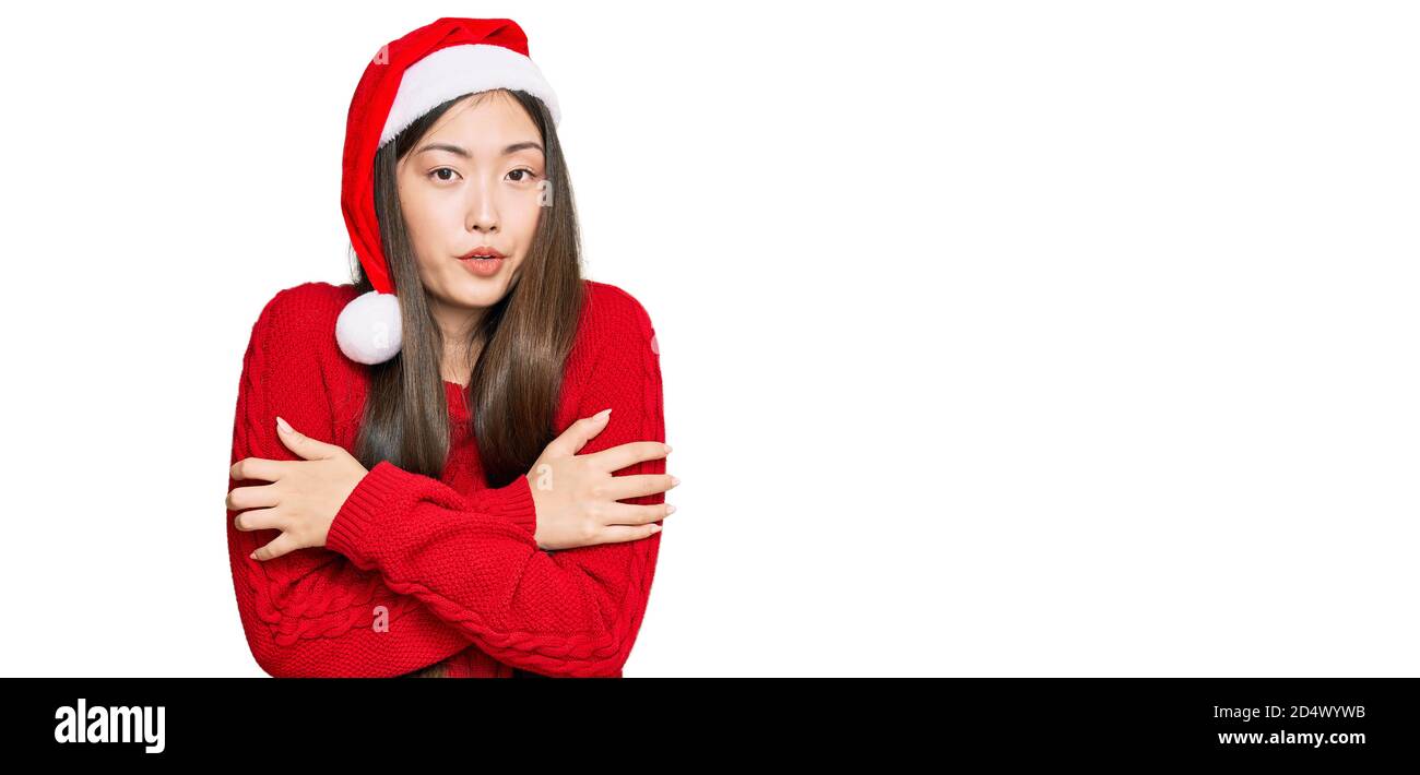 Young chinese woman wearing christmas hat shaking and freezing for ...