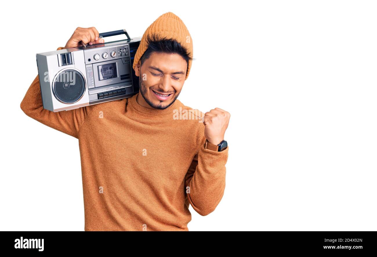 Handsome latin american young man holding boombox, listening to music ...