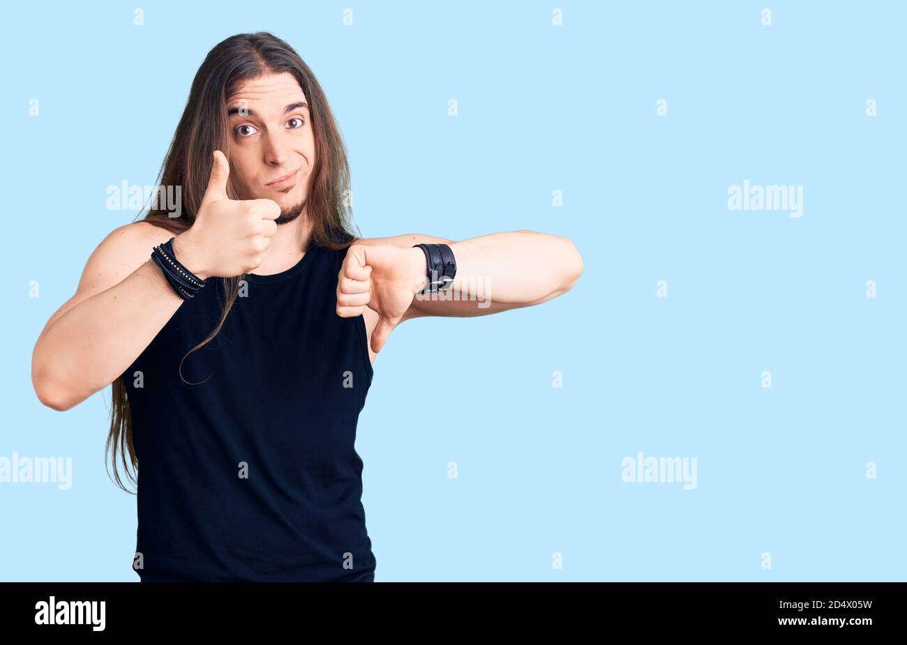 Young adult man with long hair wearing goth style with black clothes ...