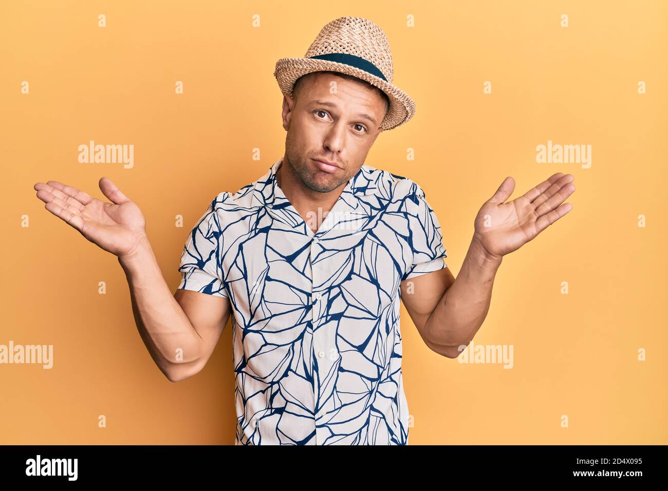 Handsome muscle man wearing summer hat clueless and confused with open ...