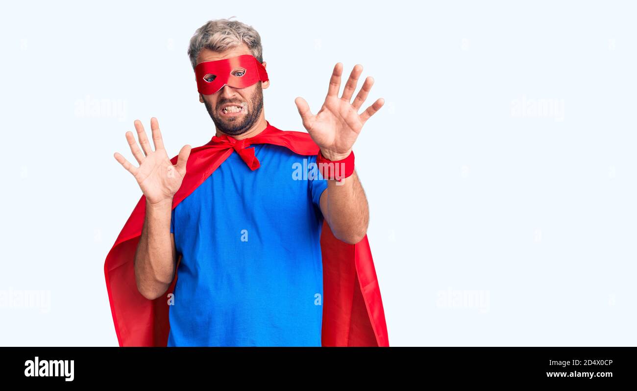 Young blond man wearing super hero custome afraid and terrified with ...