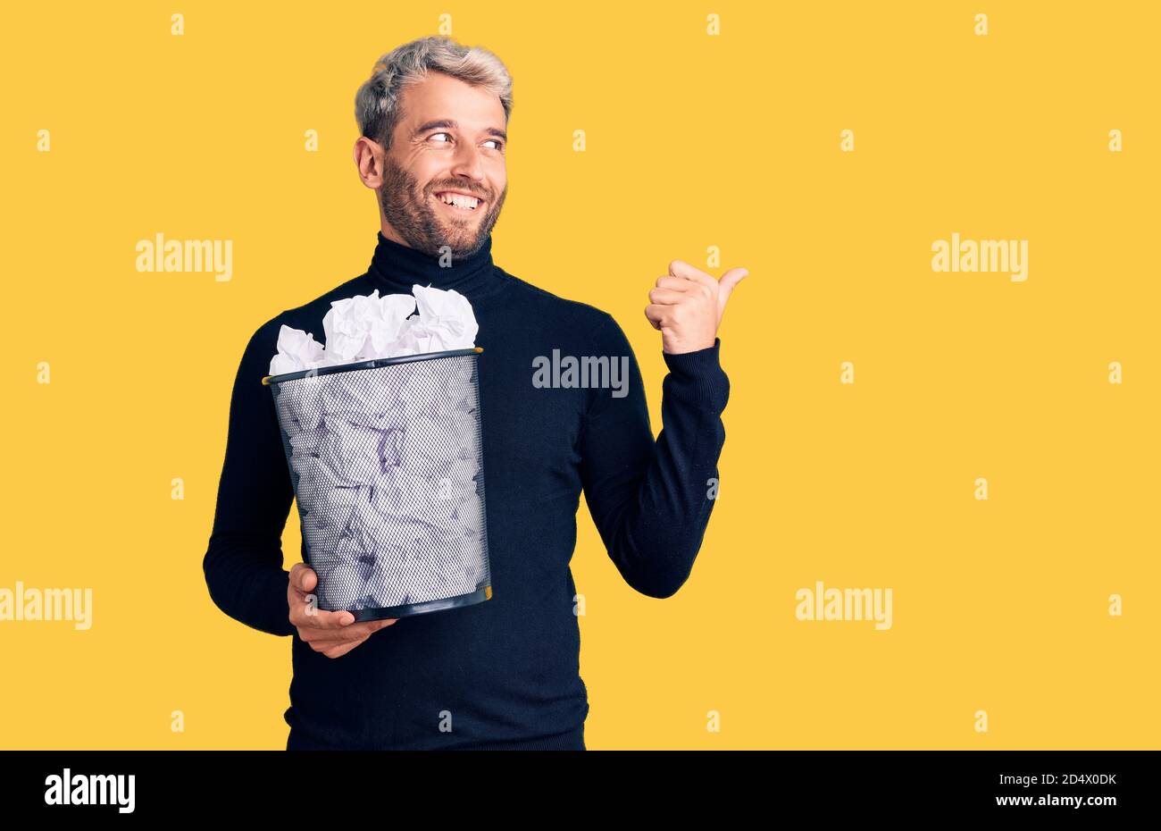 Young handsome blond man holding paper bin with crumpled papers ...