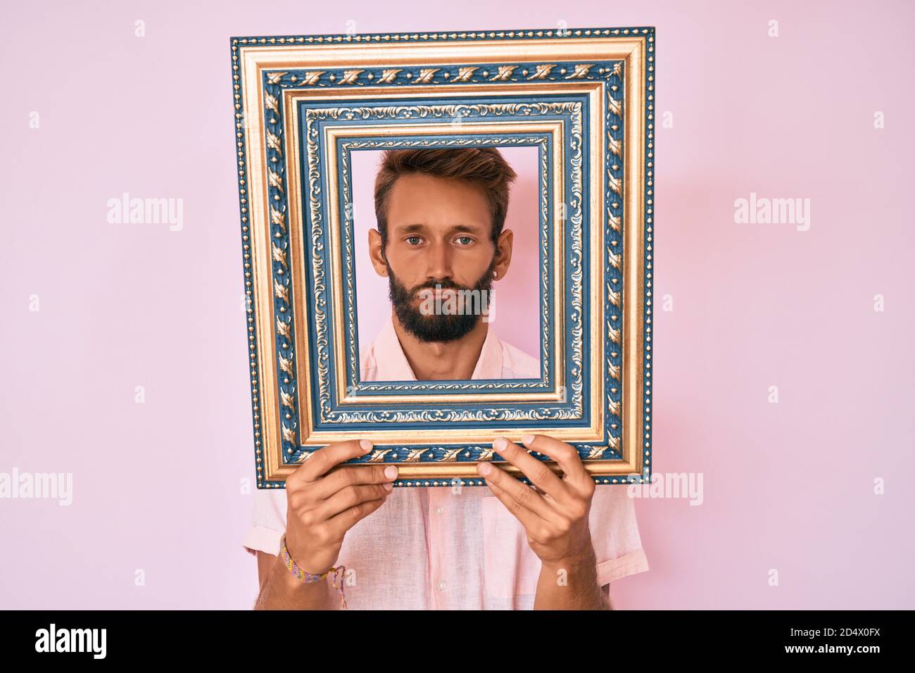 Handsome caucasian man with beard holding empty frame depressed and ...