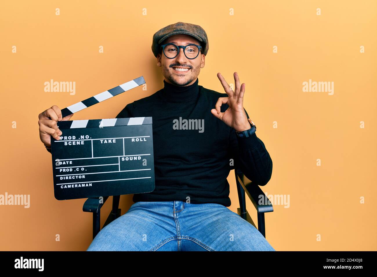 Handsome man with tattoos holding video film clapboard sitting on ...