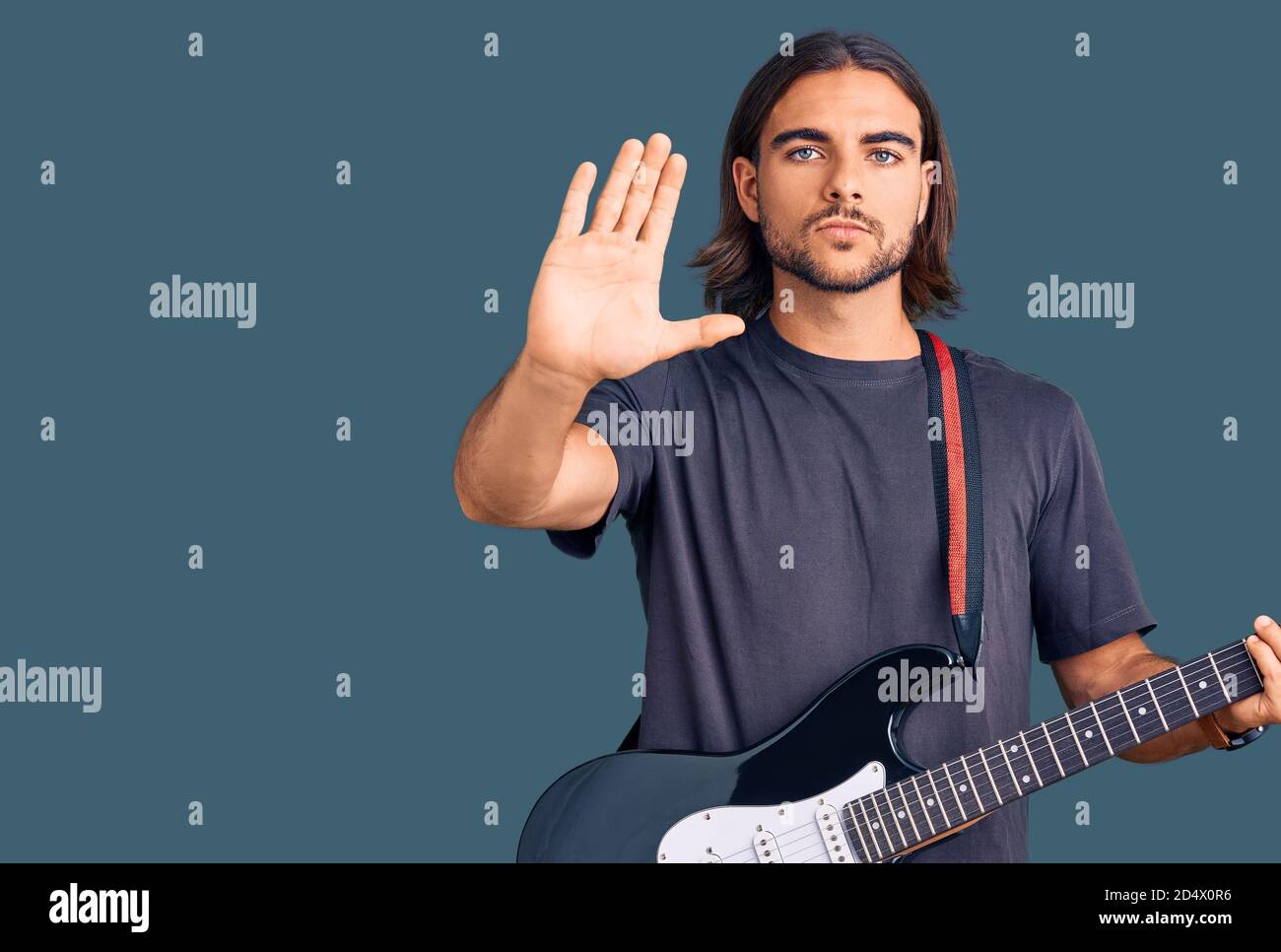 Young handsome man playing electric guitar with open hand doing stop ...