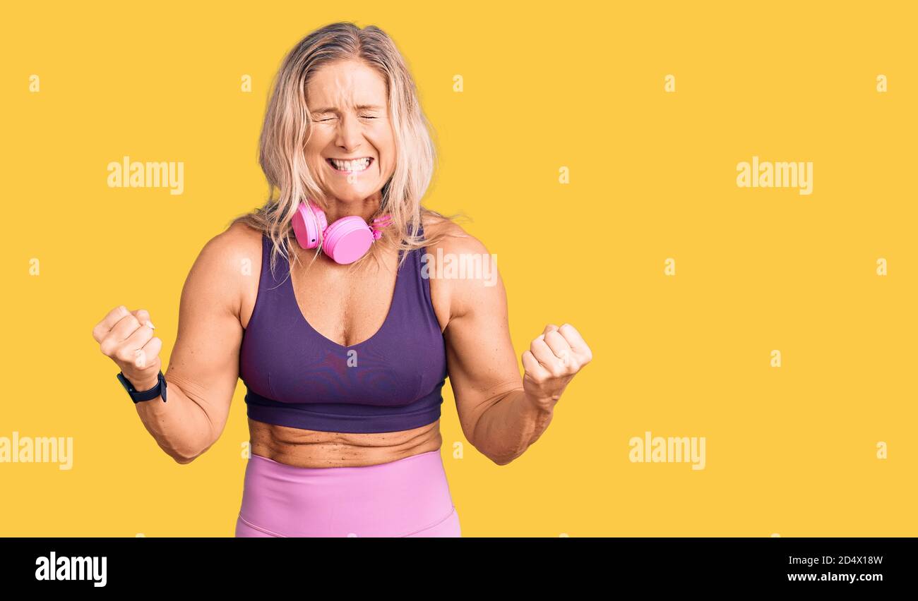 Middle age fit blonde woman wearing gym clothes and using headphones ...