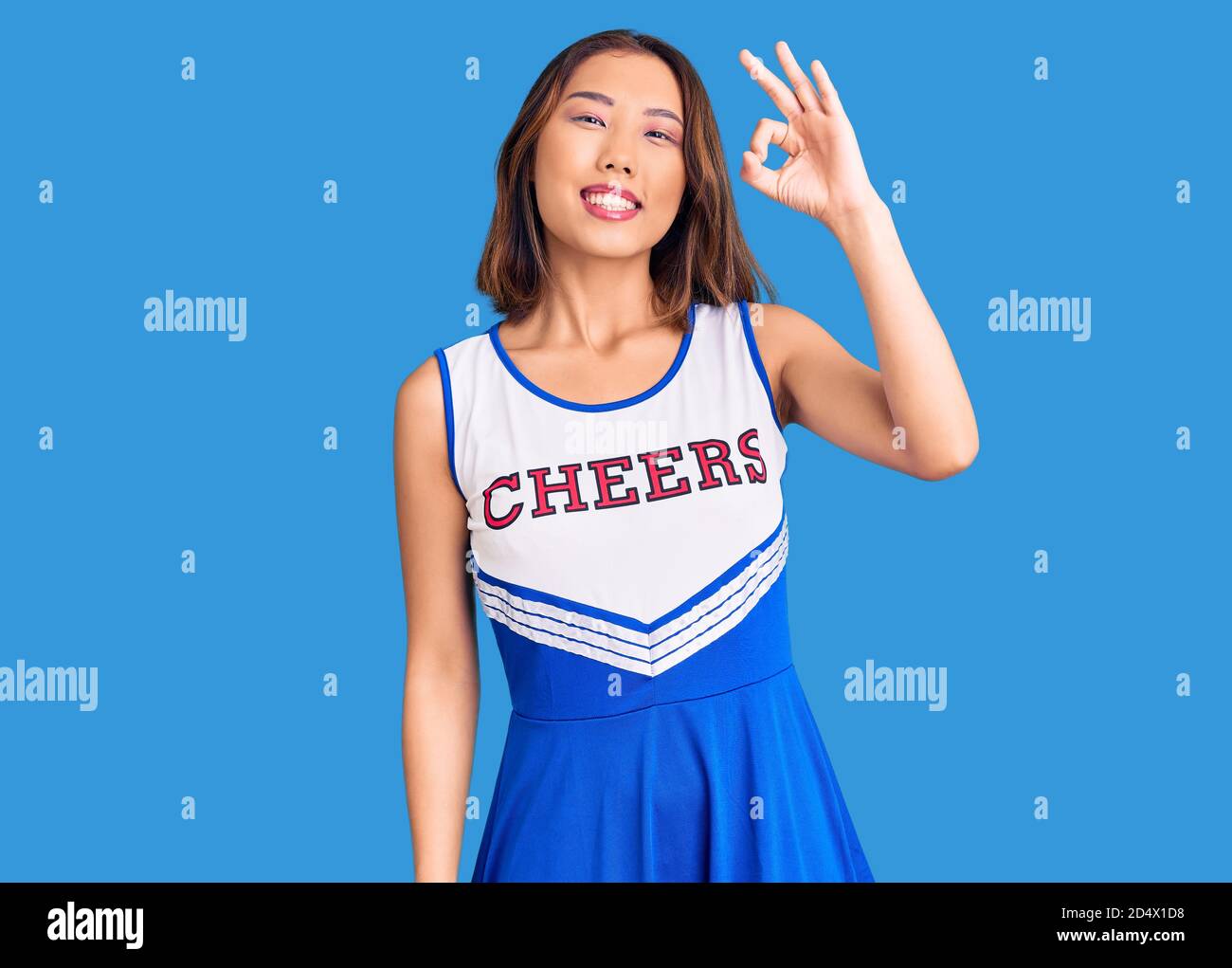 Young beautiful chinese girl wearing cheerleader uniform smiling ...