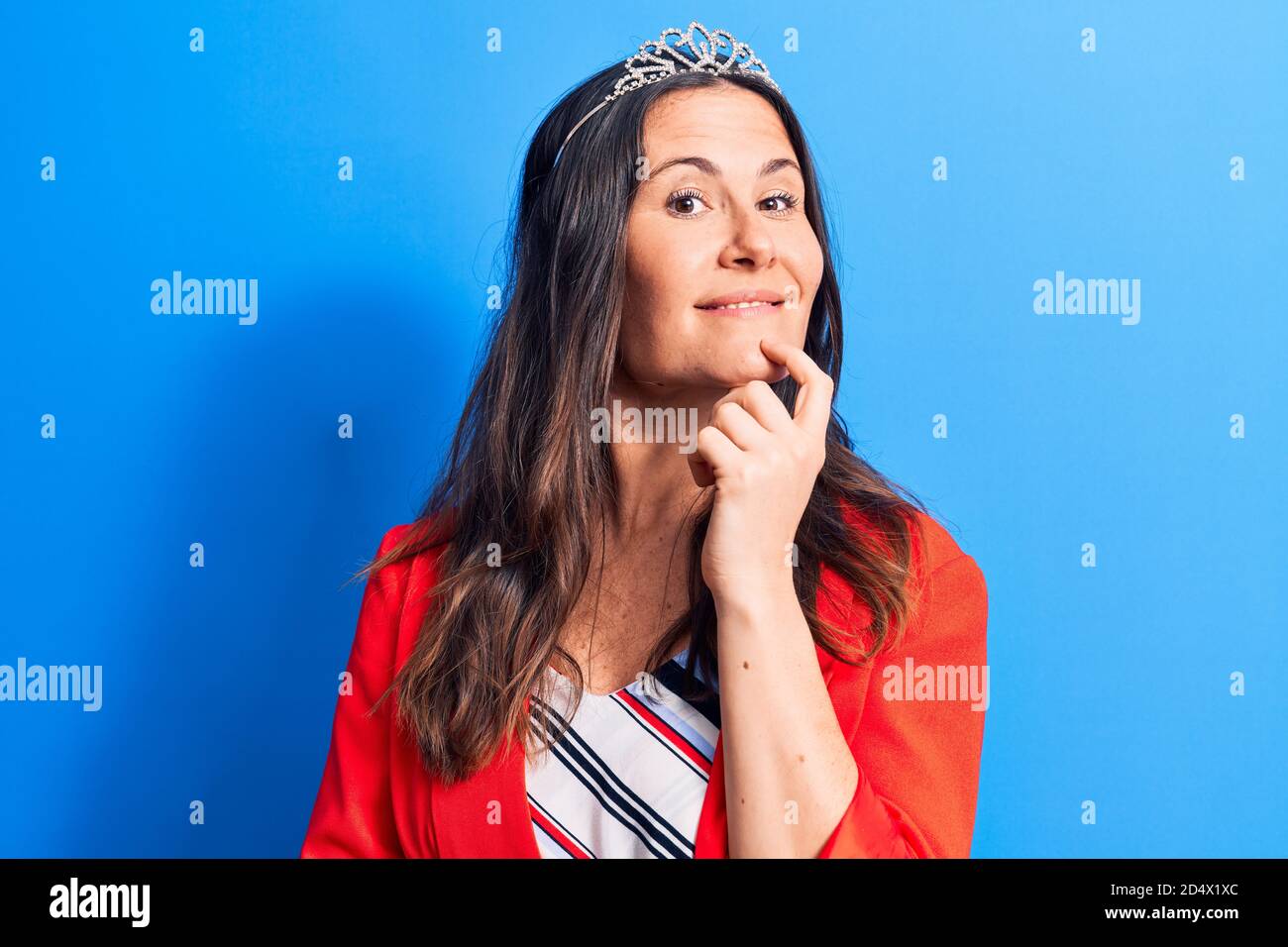Young beautiful brunette woman wearing princess crown standing over ...
