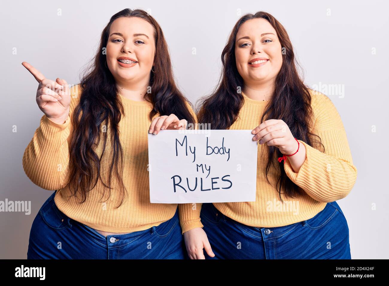 Young plus size twins holding my body my rules banner smiling happy ...