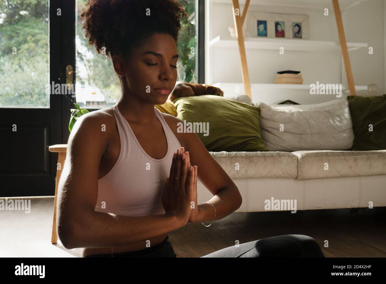 Female teen holding prayer position during yoga flow sitting in modern ...
