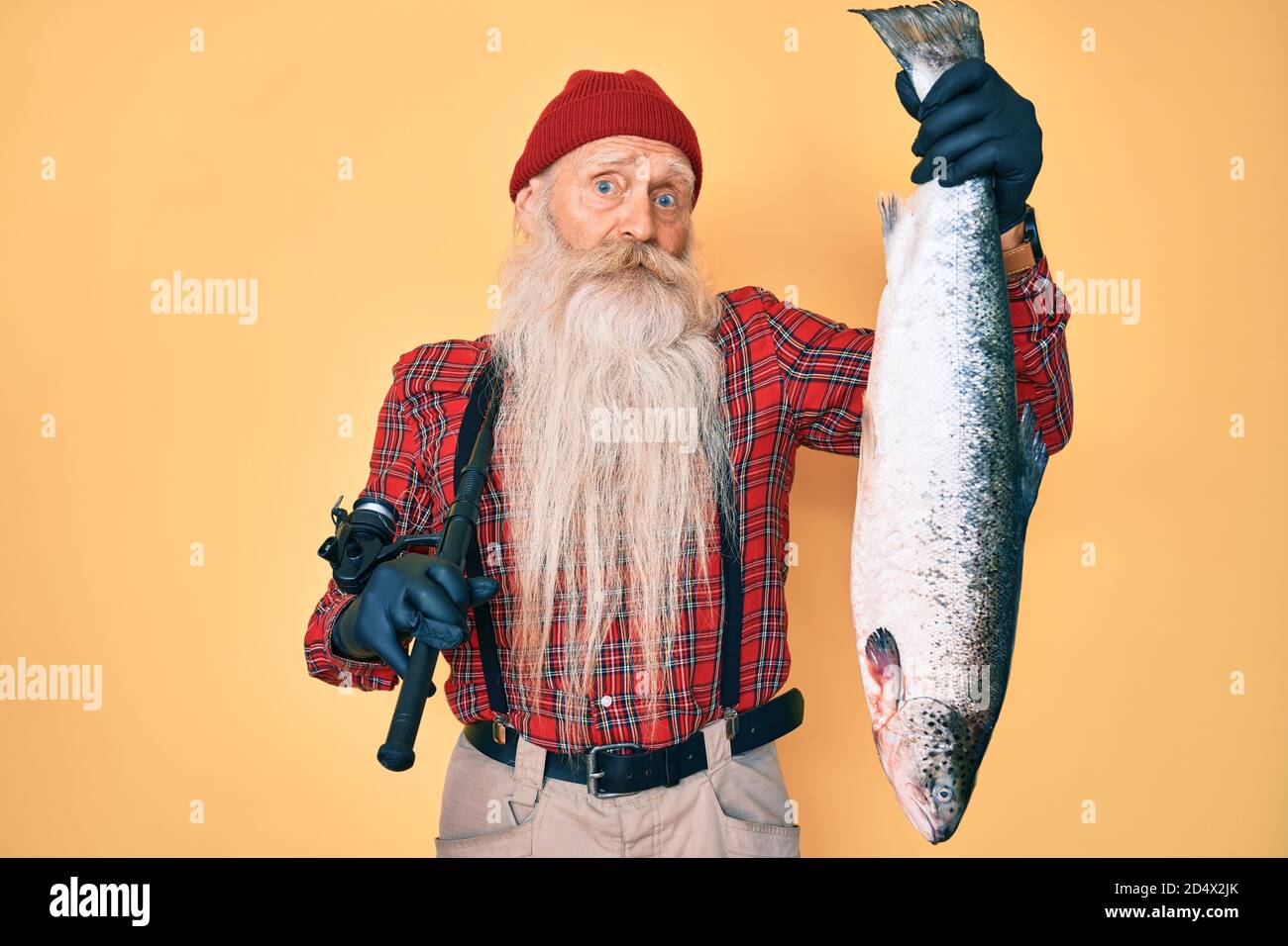 Old senior man with grey hair and long beard holding fishing rod and ...