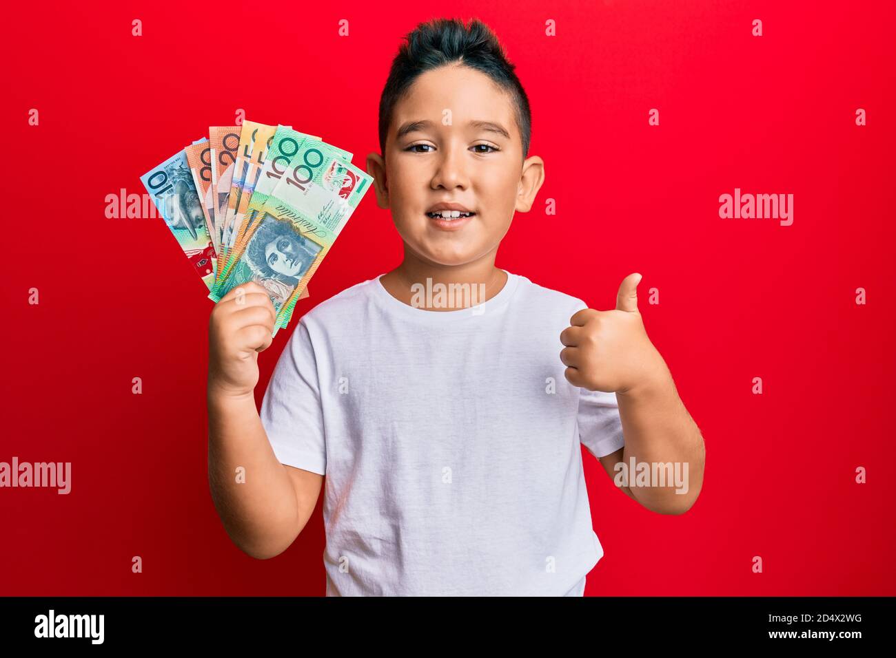 Little boy hispanic kid holding australian dollars smiling happy and ...