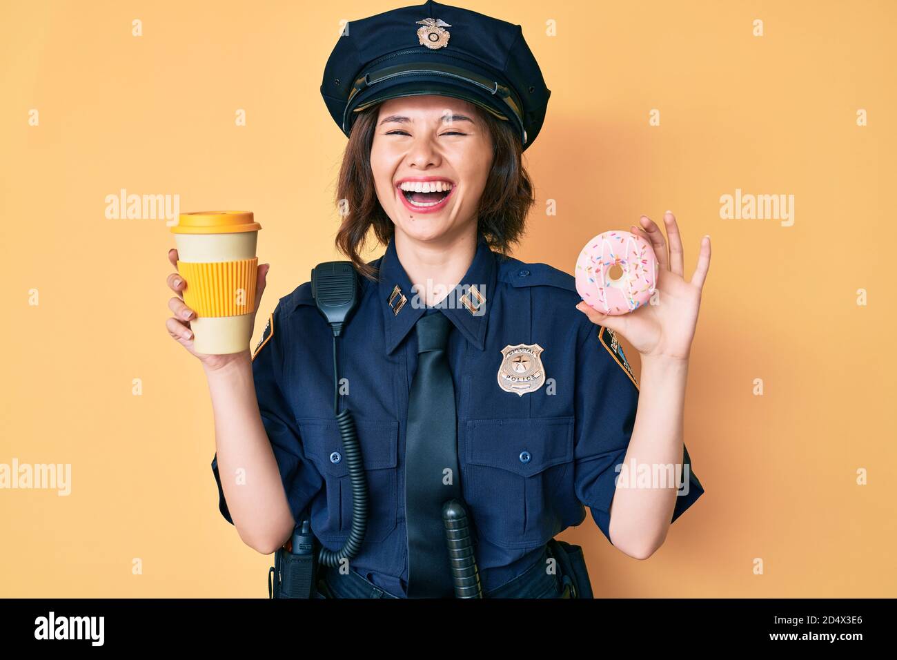 Young beautiful woman wearing police uniform holding donut and take ...