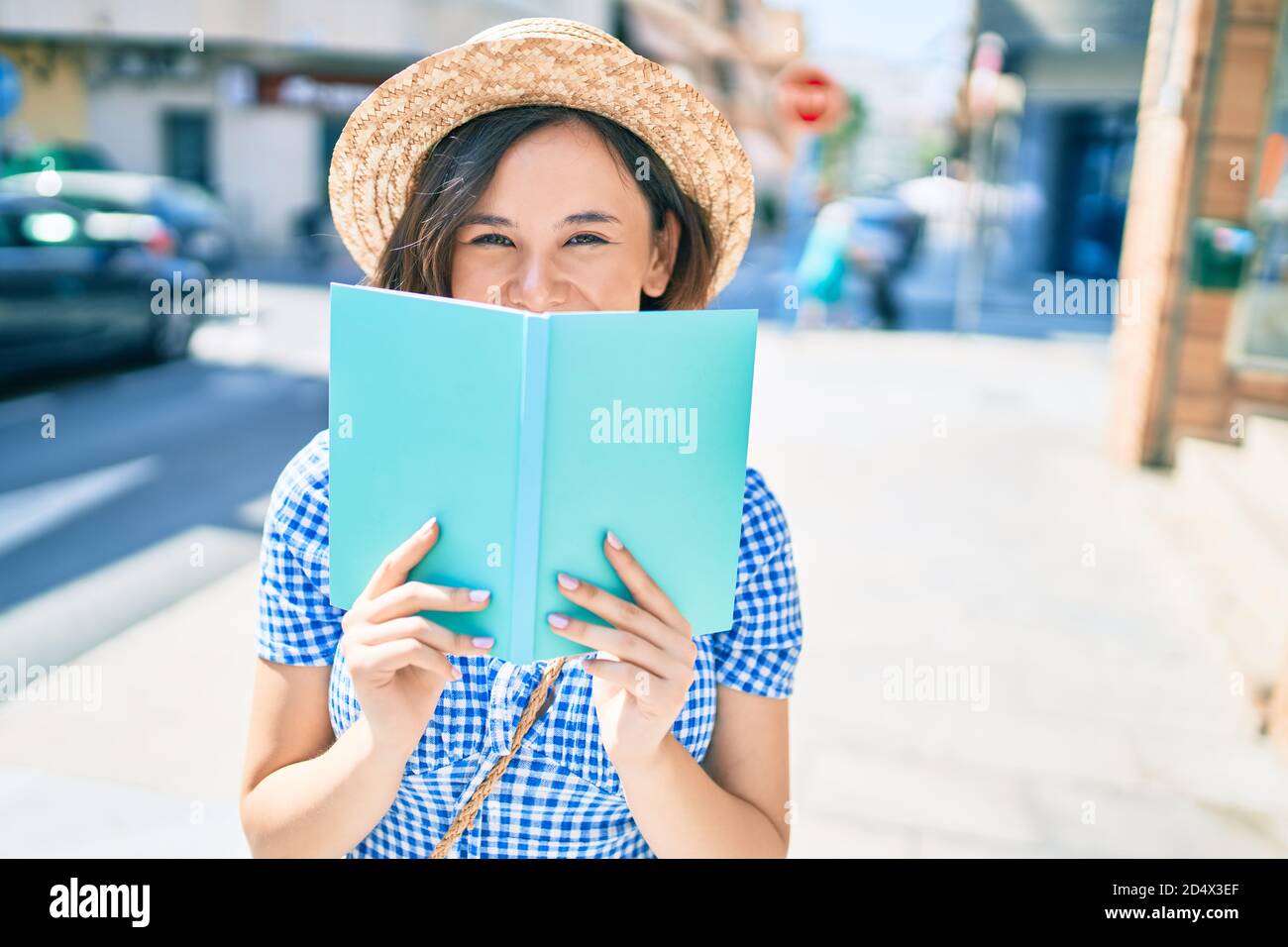 Young beautiful girl smiling happy reading book at street of city Stock ...
