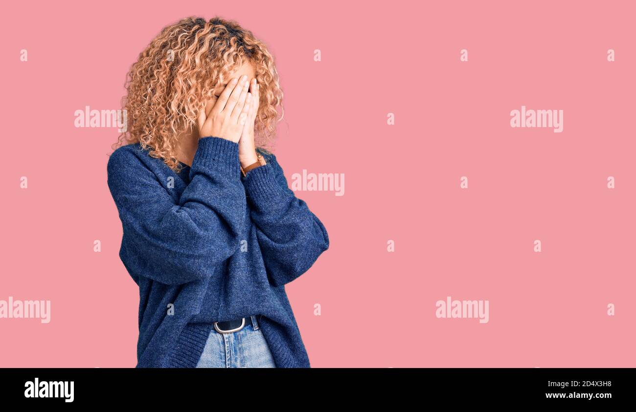 Young blonde woman with curly hair wearing casual winter sweater with ...