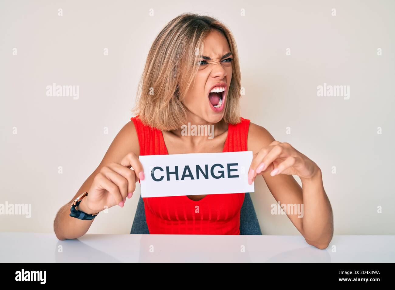 Beautiful caucasian woman holding change banner angry and mad screaming ...