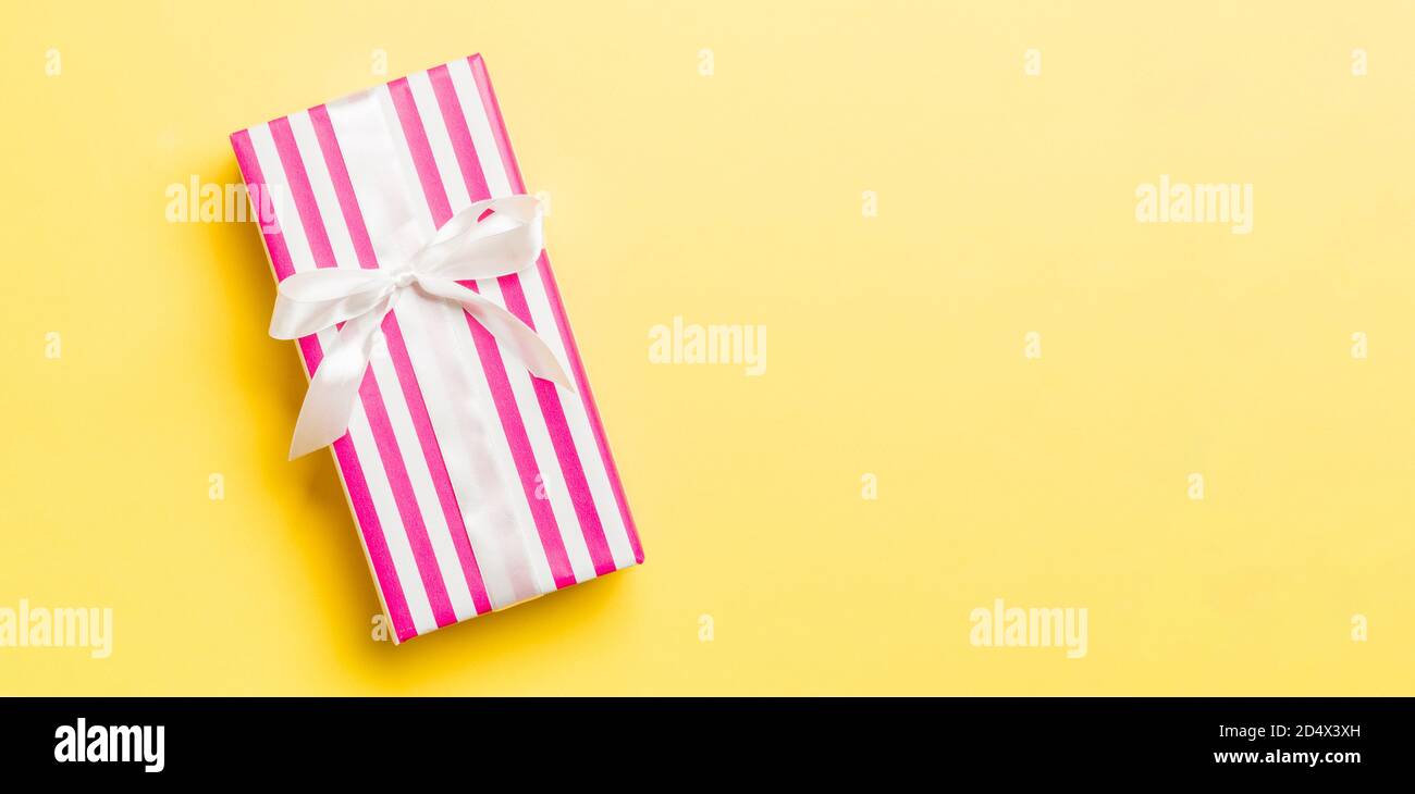 Top view Christmas present box with white bow on yellow background with ...