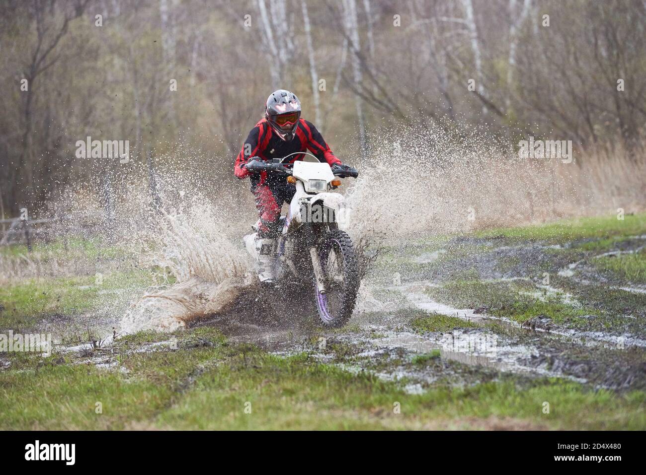 Motorcross rider racing in mud track Stock Photo - Alamy
