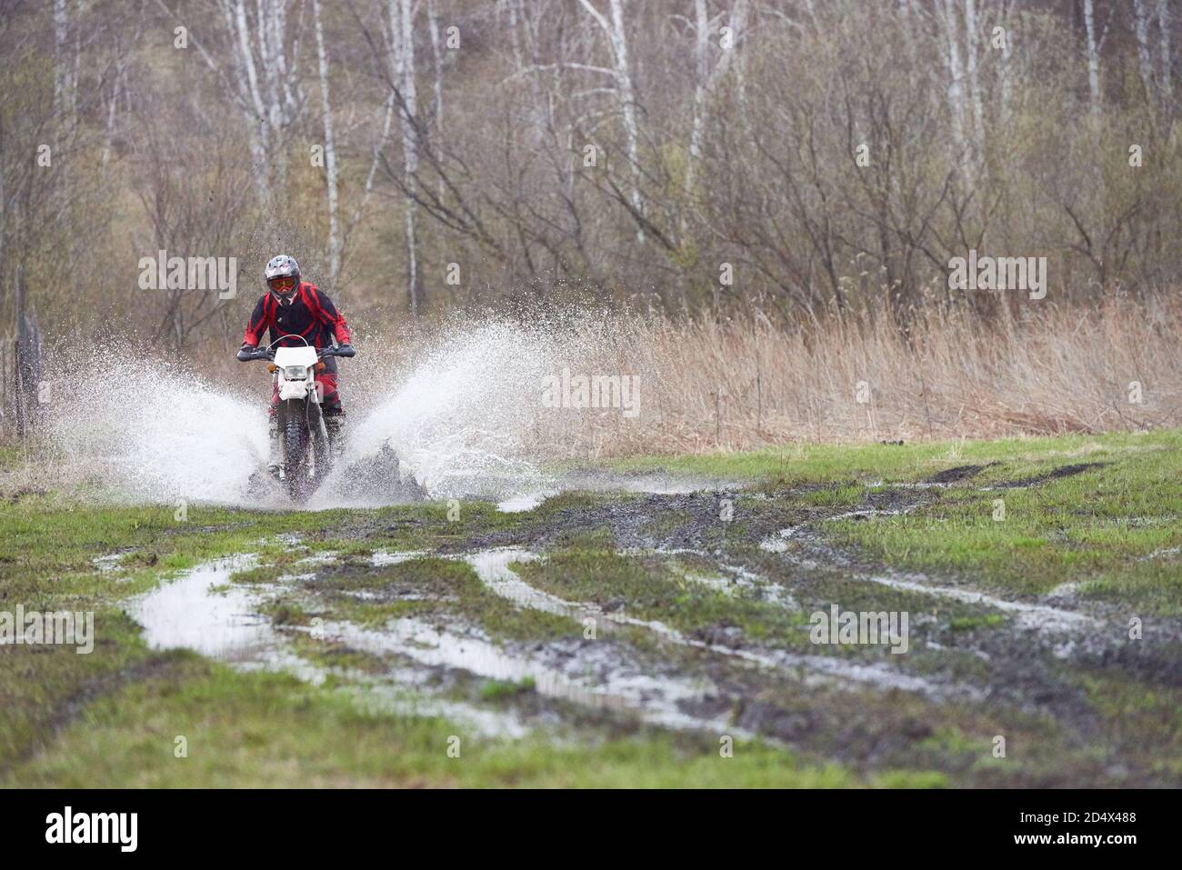 Motorcross rider racing in mud track Stock Photo - Alamy