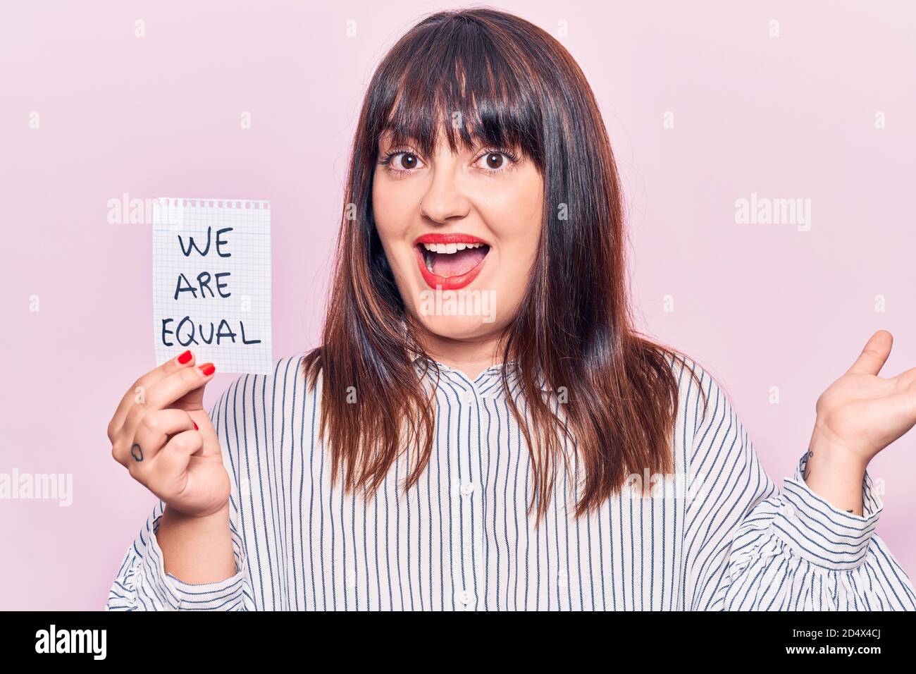 Young plus size woman holding we are equal paper celebrating ...