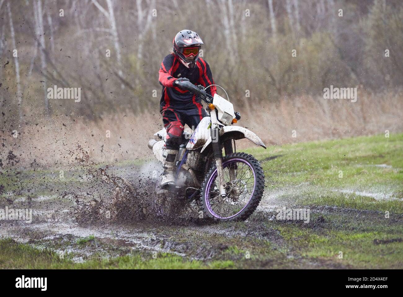 Motorcross rider racing in mud track Stock Photo - Alamy