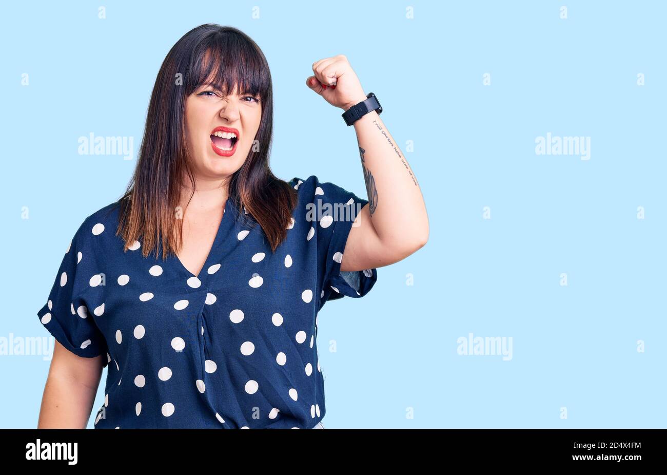 Young plus size woman wearing casual clothes angry and mad raising fist ...