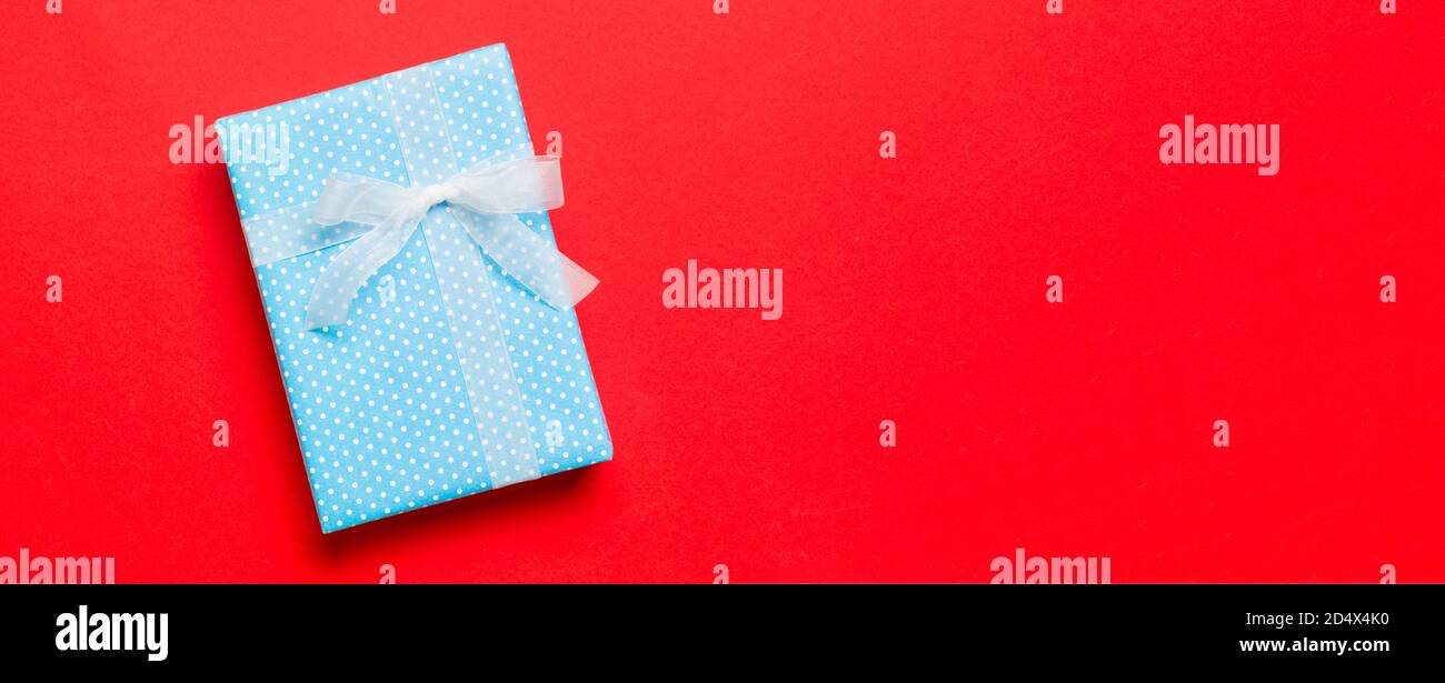 Top view Christmas present box with white bow on red background with ...