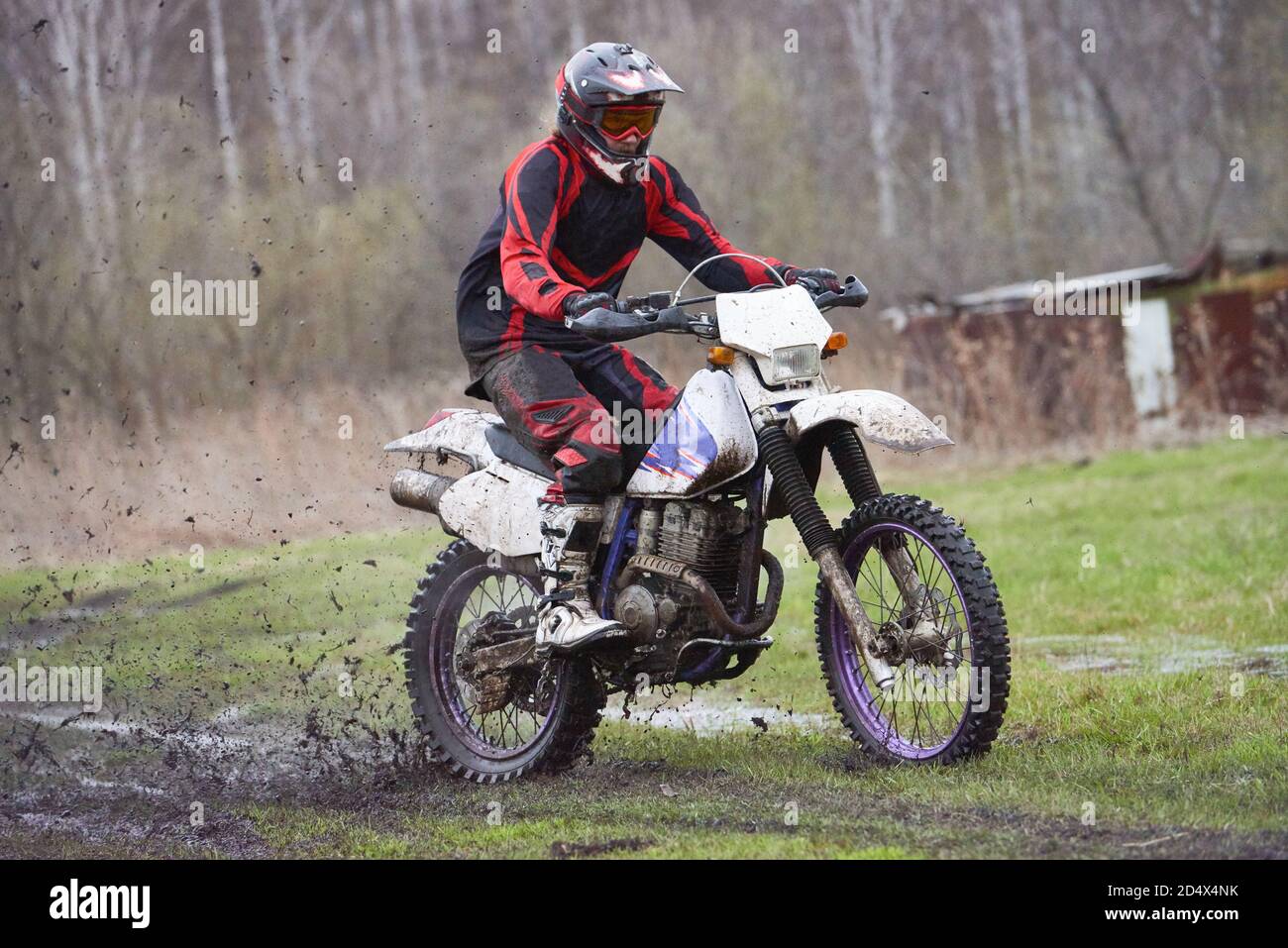 Motorcross rider racing in mud track Stock Photo - Alamy