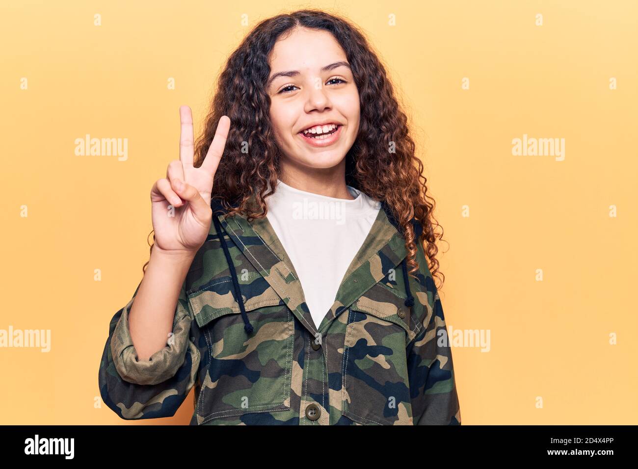 Beautiful kid girl with curly hair wearing camouflage jacket smiling ...