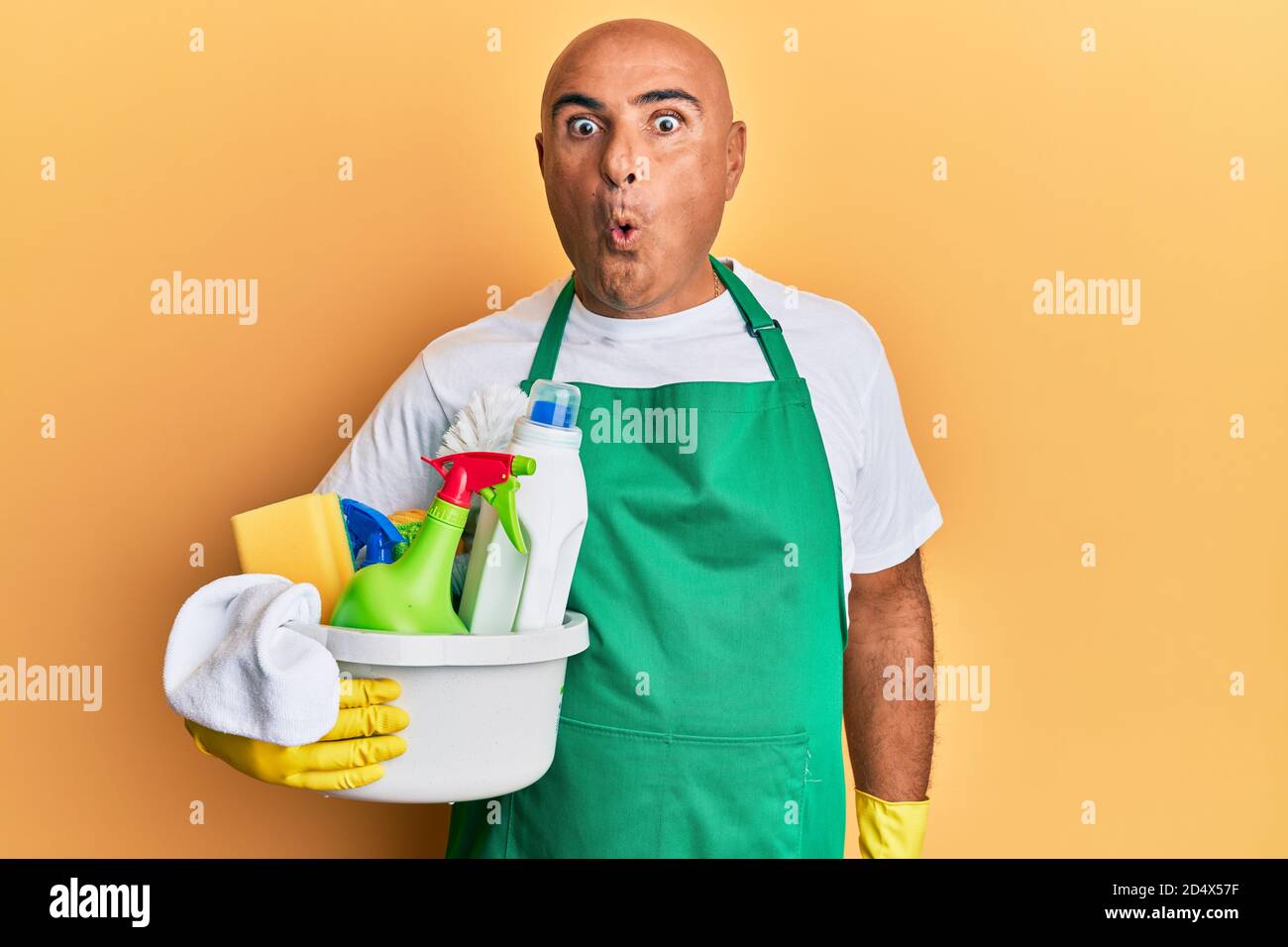 Mature middle east man wearing cleaner apron holding cleaning products ...