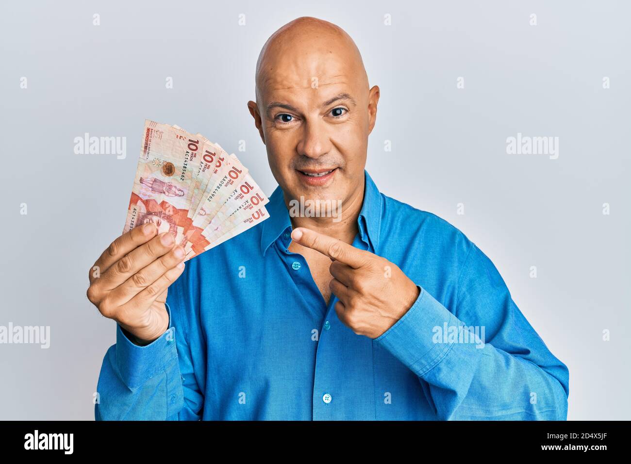 Middle age bald man holding 10 colombian pesos banknotes smiling happy ...