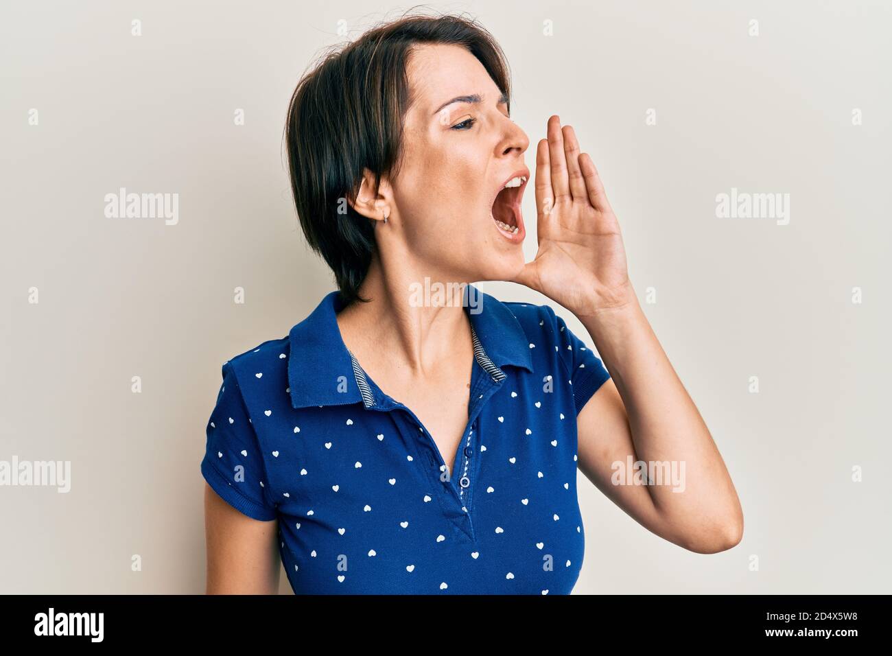 Young brunette woman with short hair wearing casual clothes shouting ...