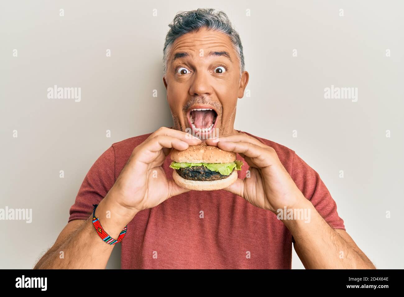 Handsome middle age mature man eating a tasty classic burger ...