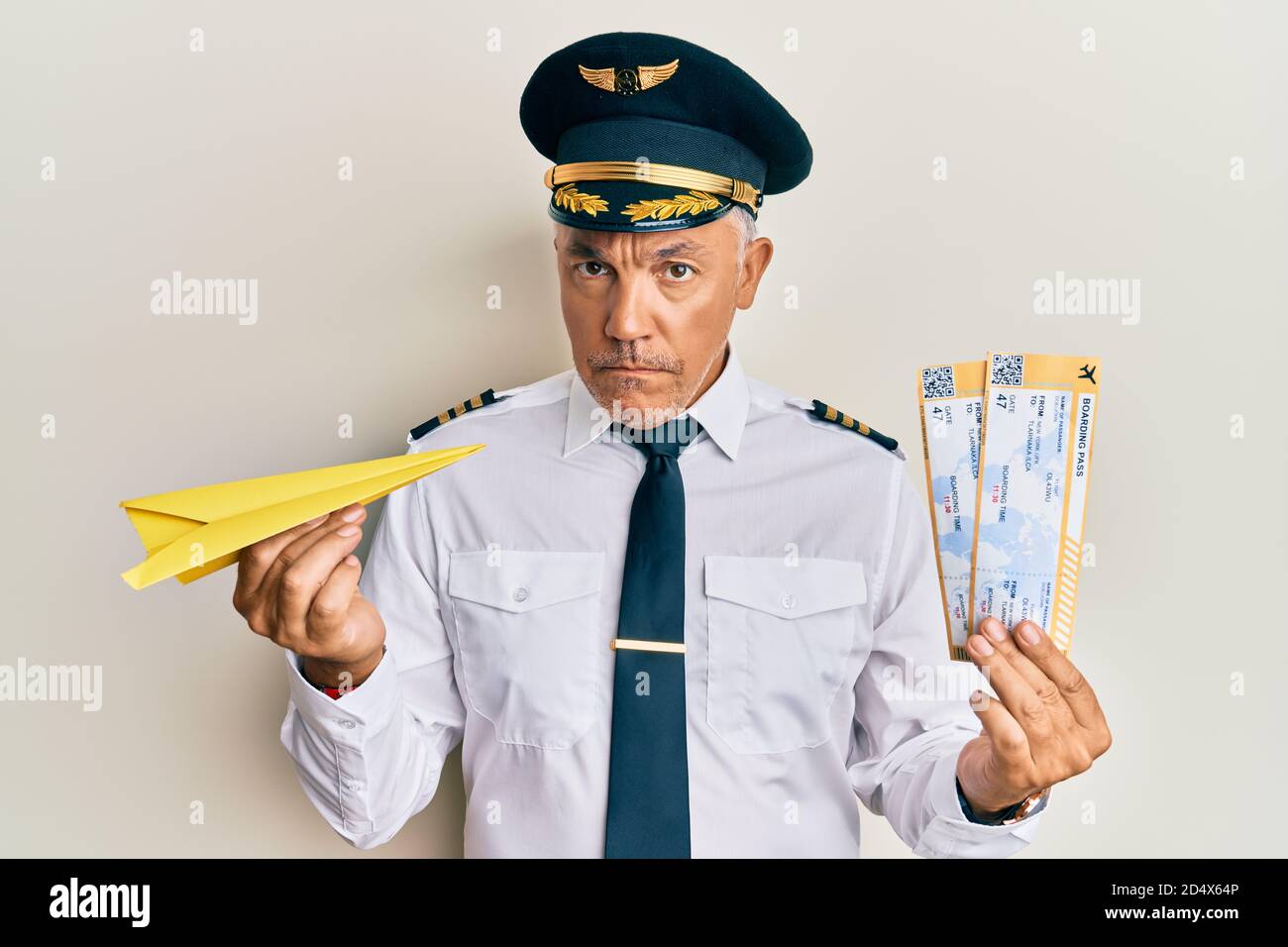Handsome middle age mature pilot man holding paper plane and boarding ...