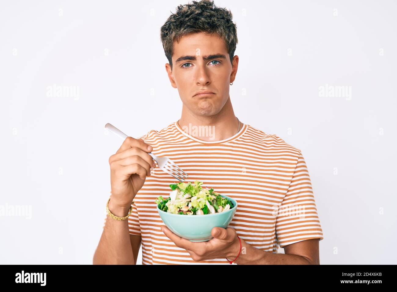Young handsome man eating salad depressed and worry for distress ...
