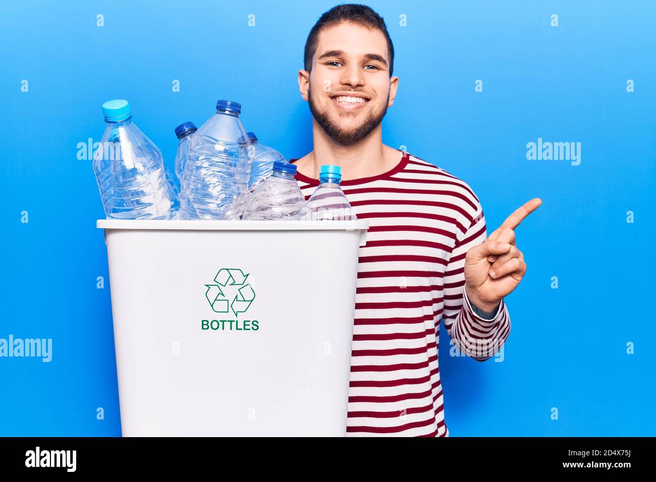 Young handsome man recycling plastic bottles smiling happy pointing ...