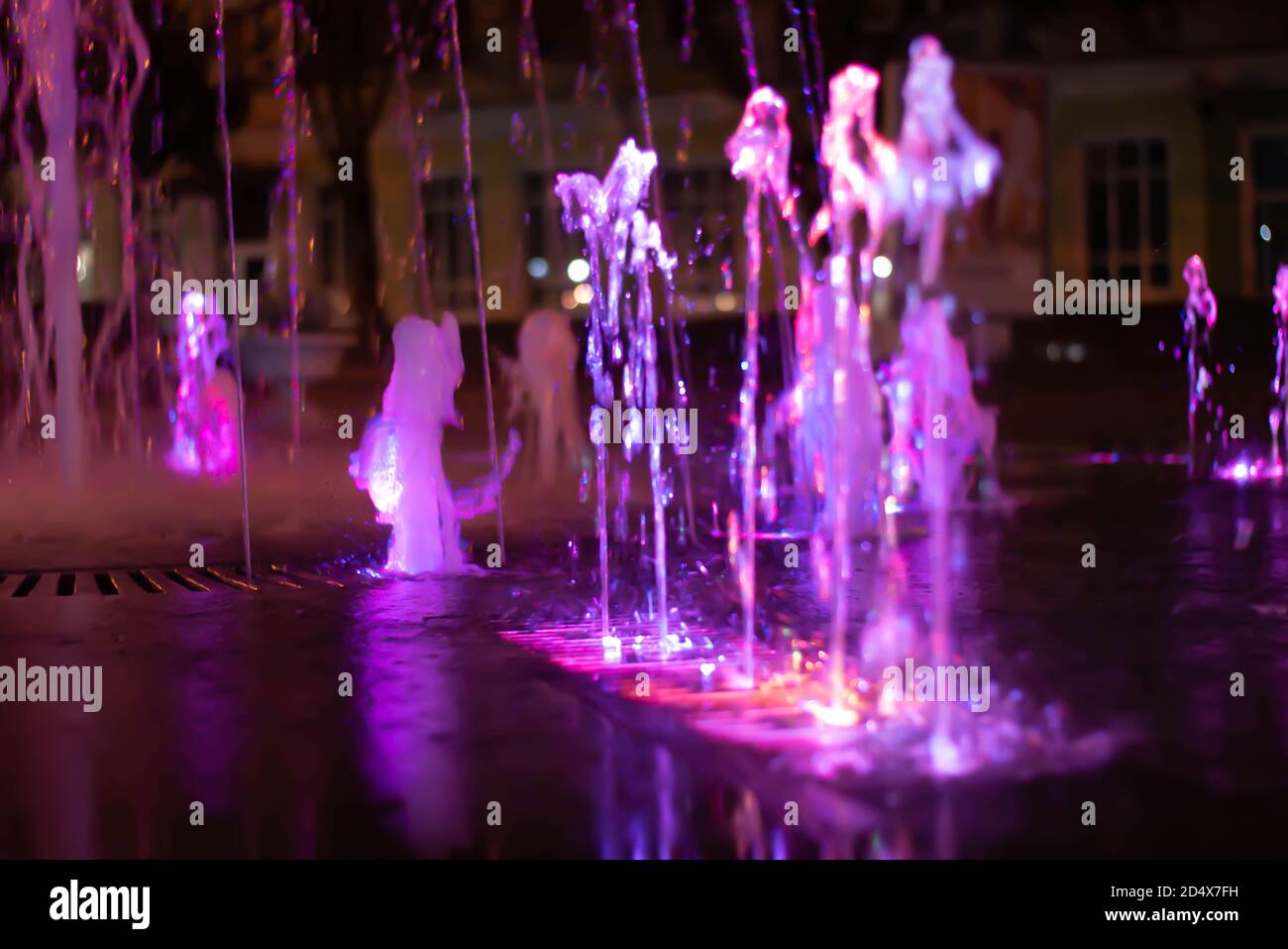 Blurry jets of water at night in the light of colored lanterns. Bokeh ...