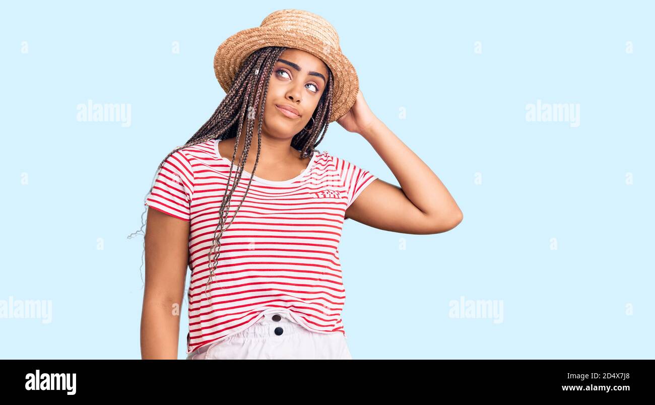 Young african american woman with braids wearing summer hat confuse and ...