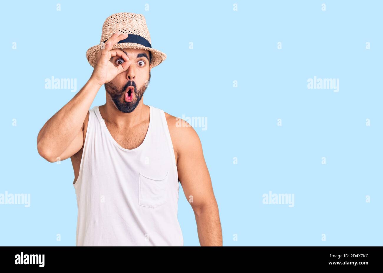 Young hispanic man wearing casual summer hat doing ok gesture shocked ...