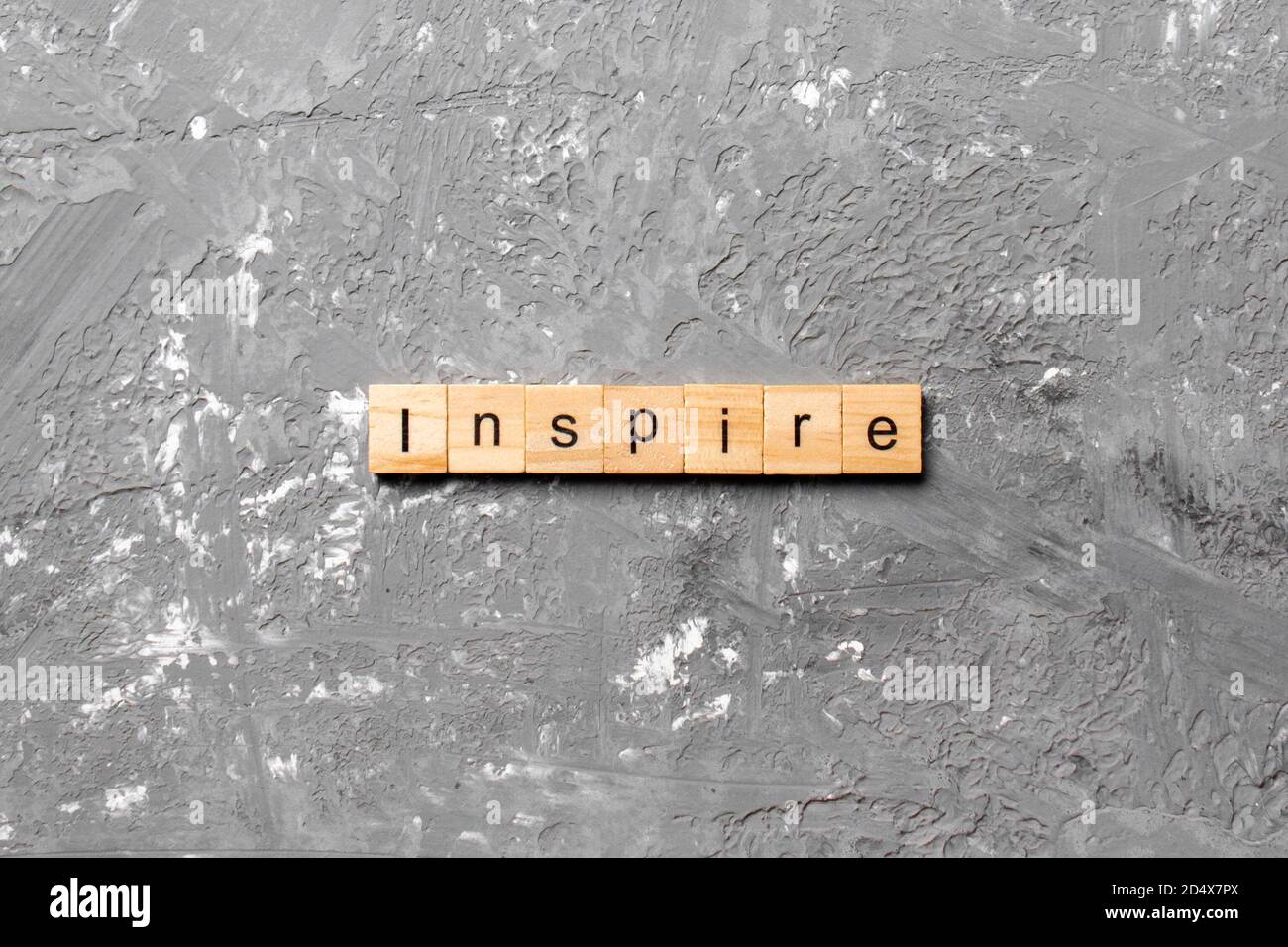 Inspire word written on wood block. Inspire text on cement table for ...