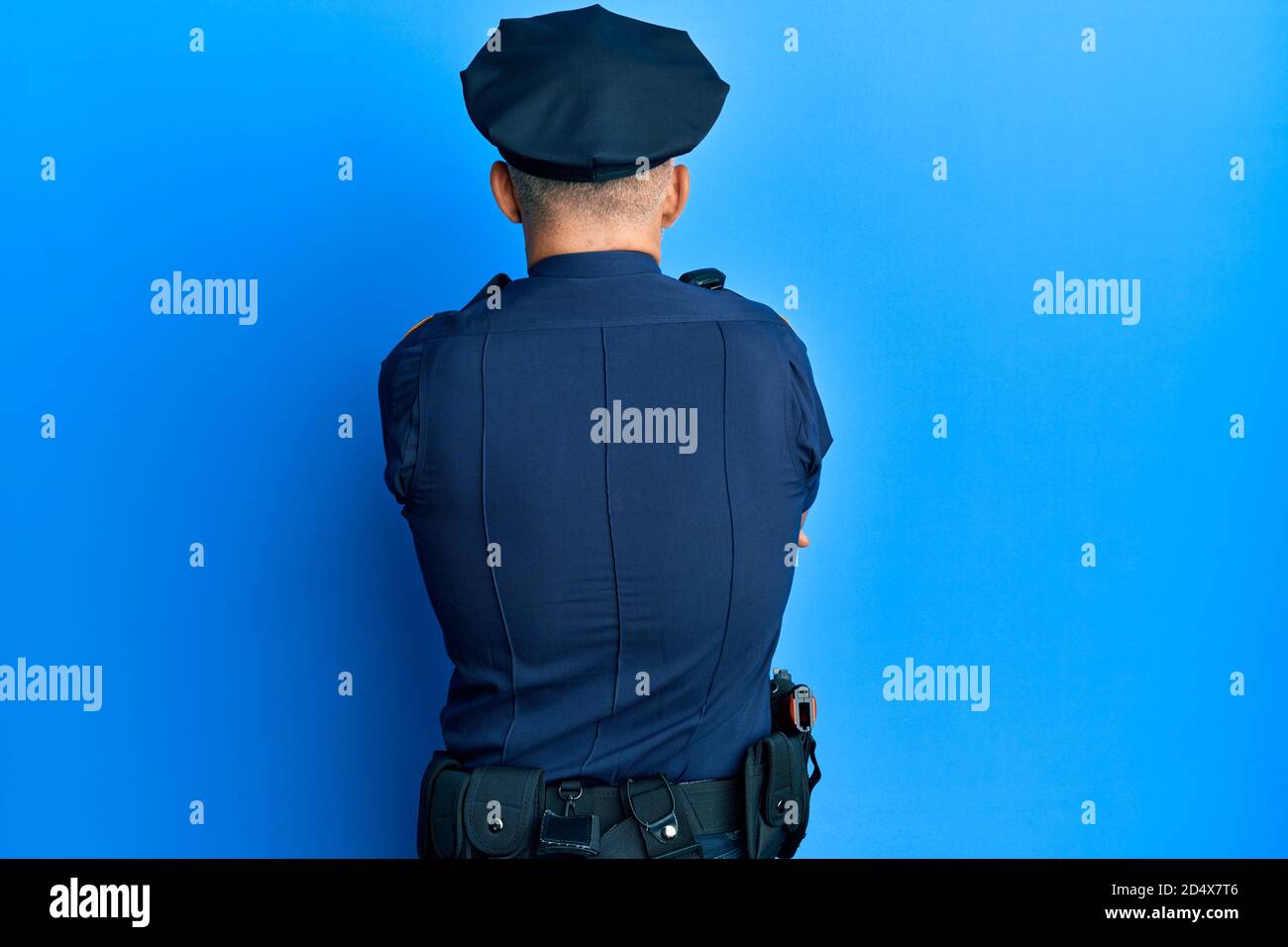 Middle age handsome man wearing police uniform standing backwards ...