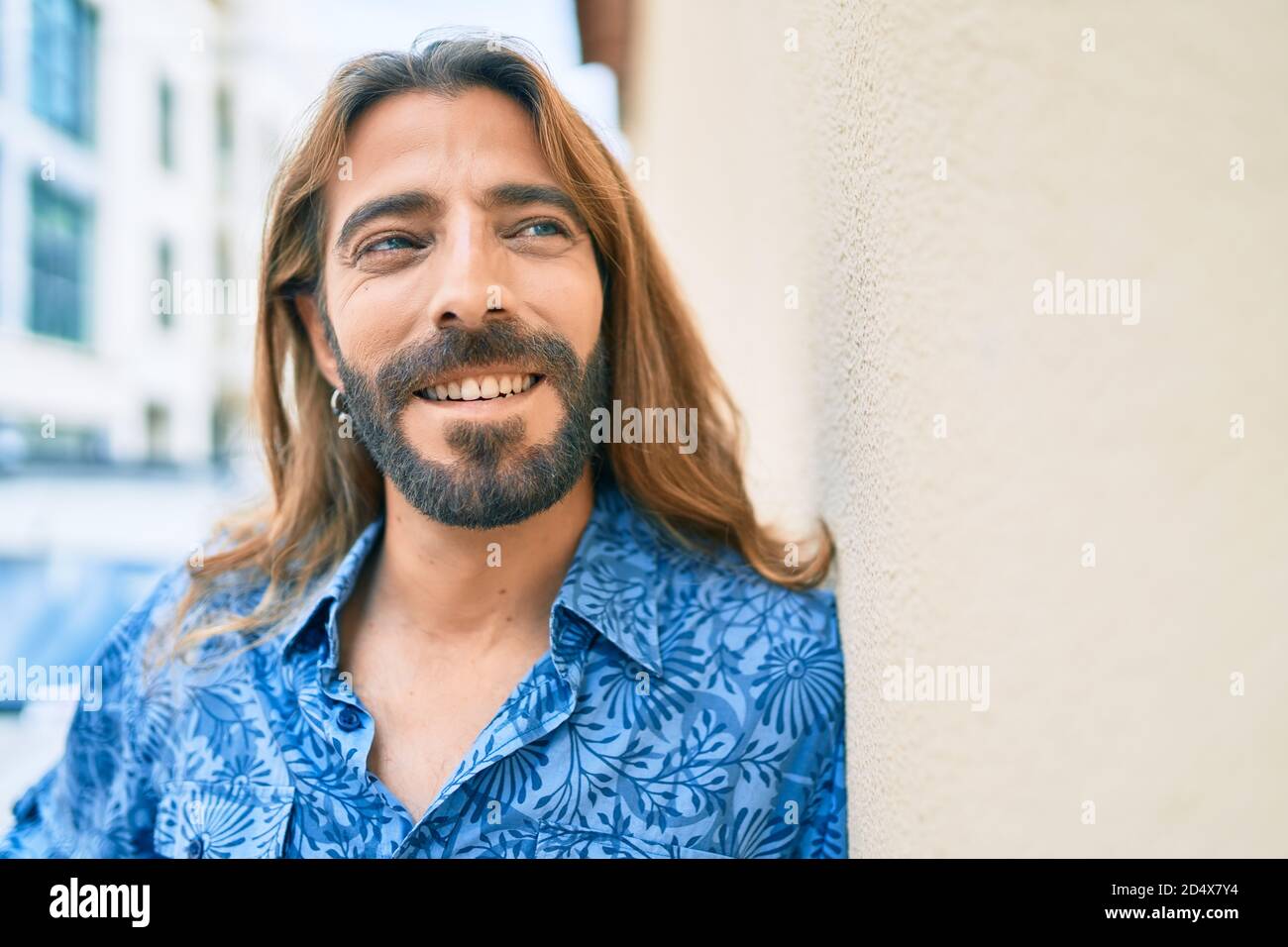 Young middle eastern man smiling happy leaning on the wall at the city ...