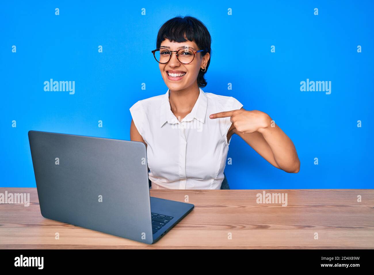 Beautiful brunettte woman working using computer laptop pointing finger ...