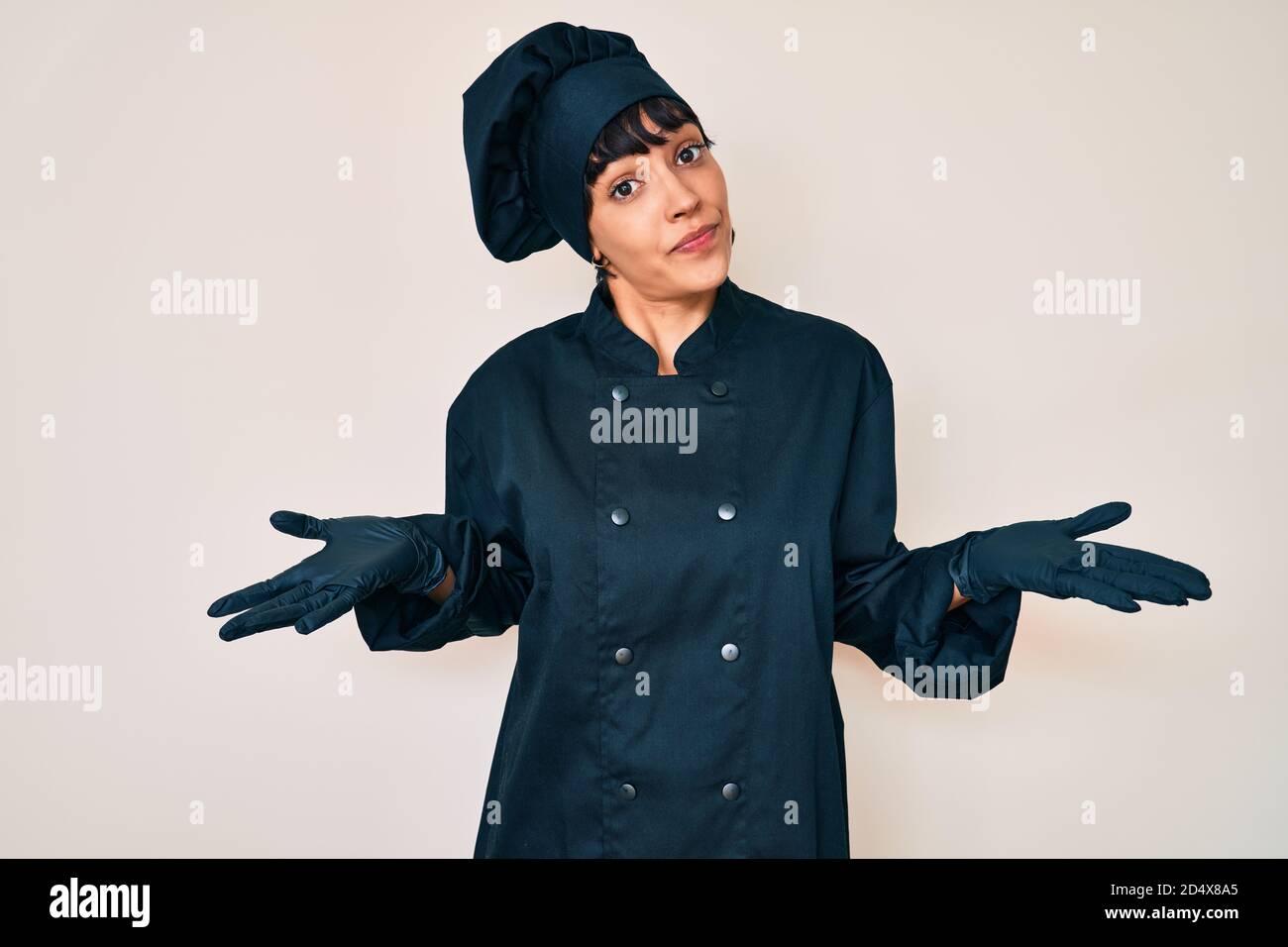 Beautiful brunettte woman wearing professional cook uniform clueless ...