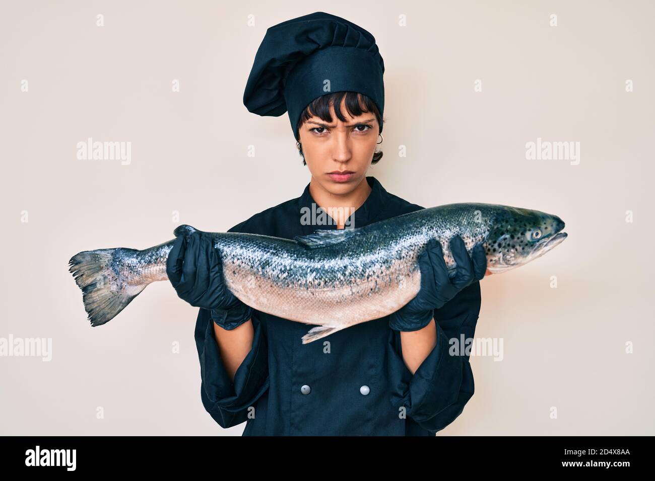 Beautiful brunettte woman professional chef holding fresh salmon fish ...