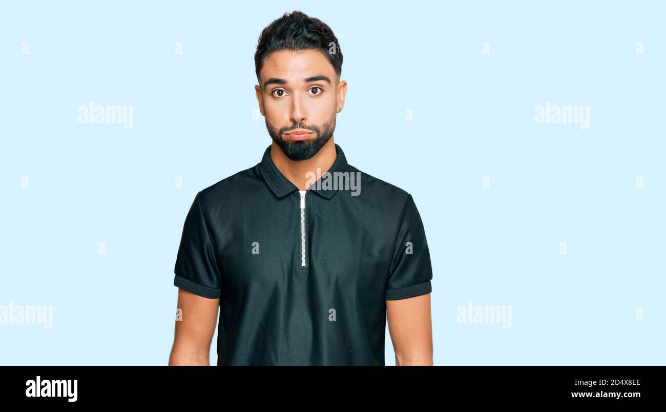 Young man with beard wearing sportswear puffing cheeks with funny face ...