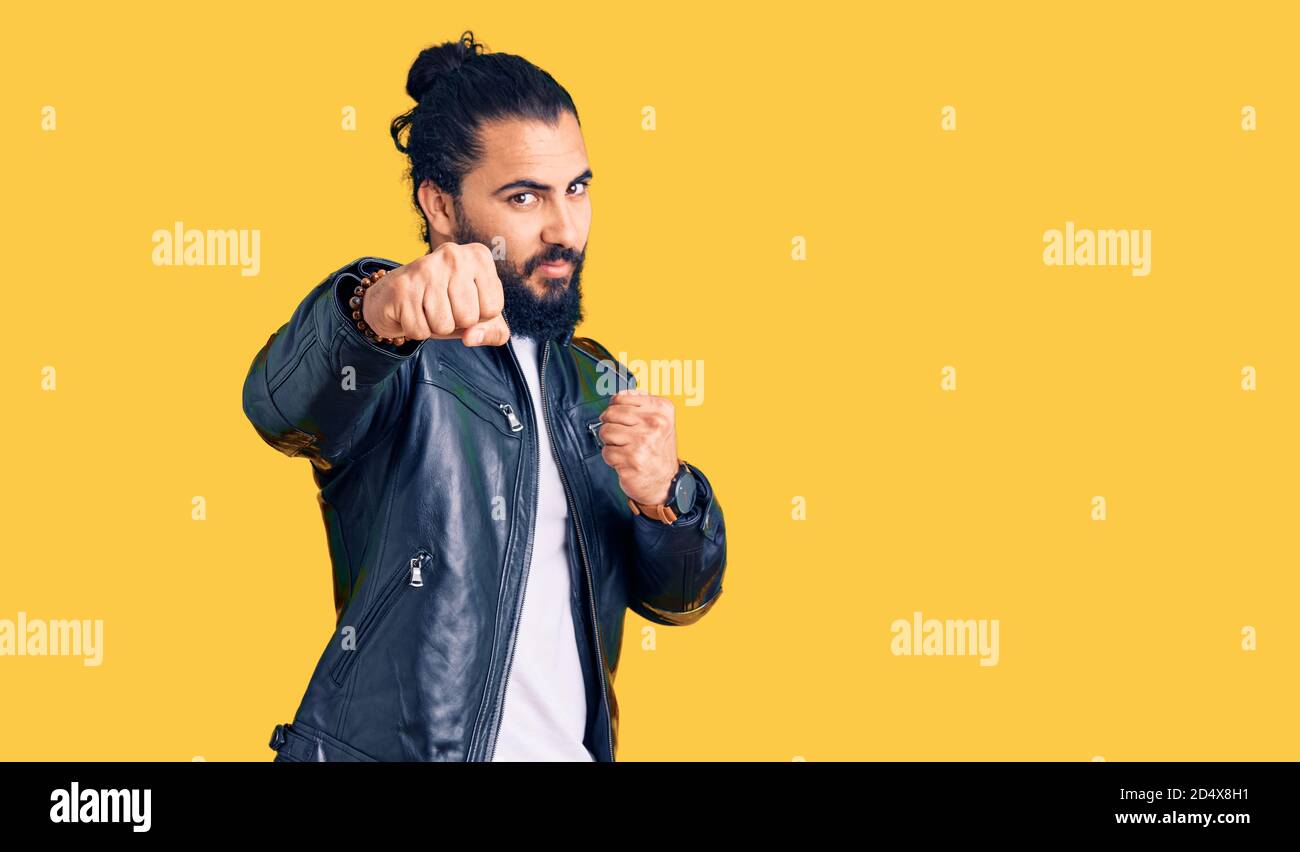 Young arab man wearing casual leather jacket punching fist to fight ...