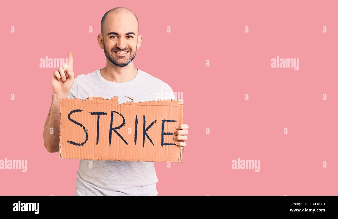 Young handsome man holding strike banner surprised with an idea or ...